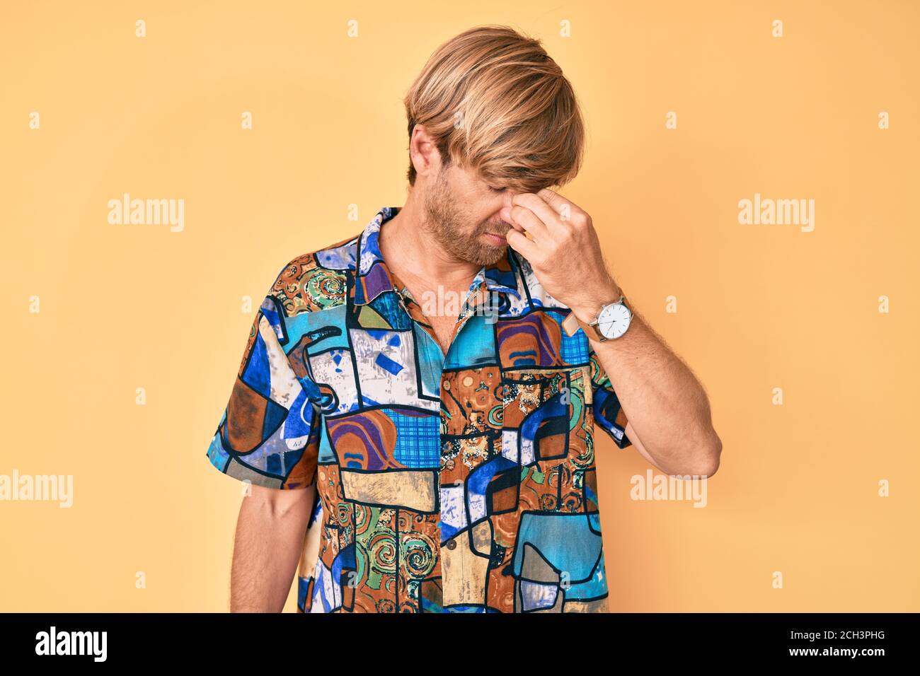 Young blond man wearing summer shirt tired rubbing nose and eyes ...