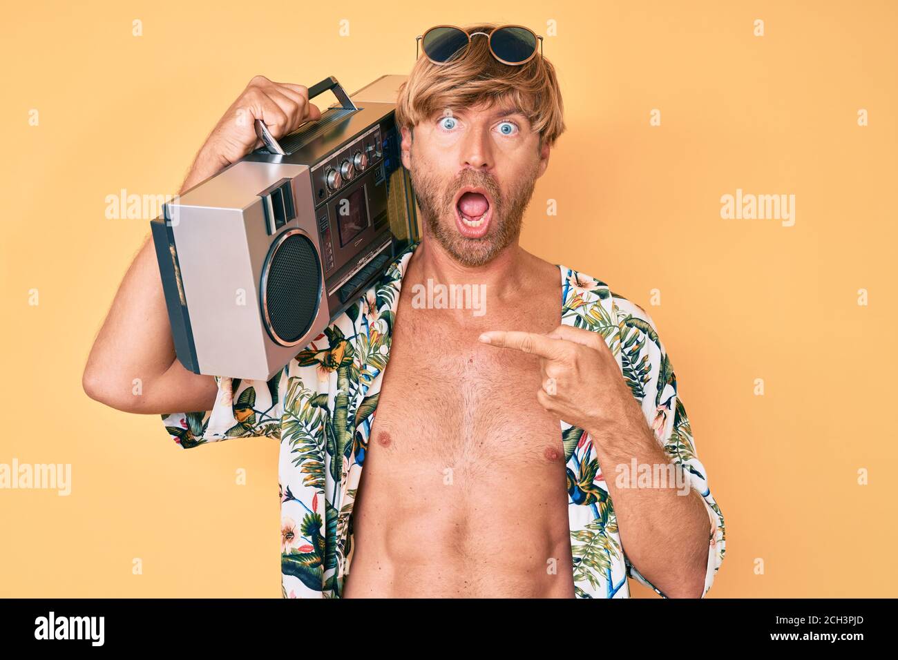 Young blond man wearing summer style holding boom box afraid and ...