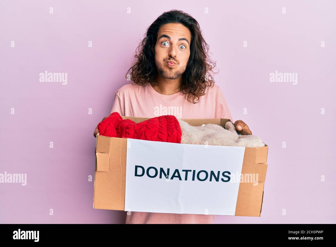 Young handsome man with long hair holding donations box for charity ...