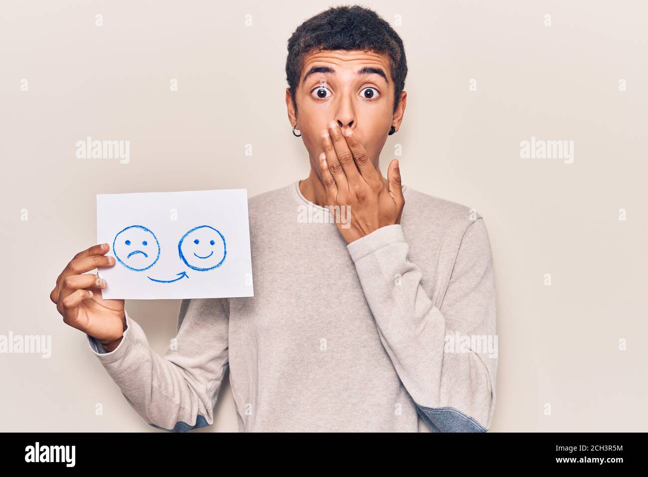 Young african amercian man holding sad to happy emotion paper covering ...