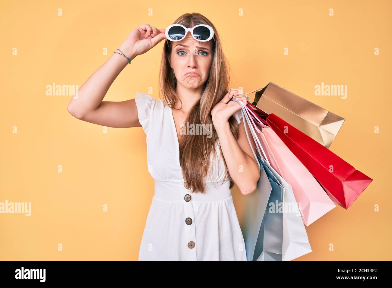 Young blonde girl holding shopping bags depressed and worry for ...