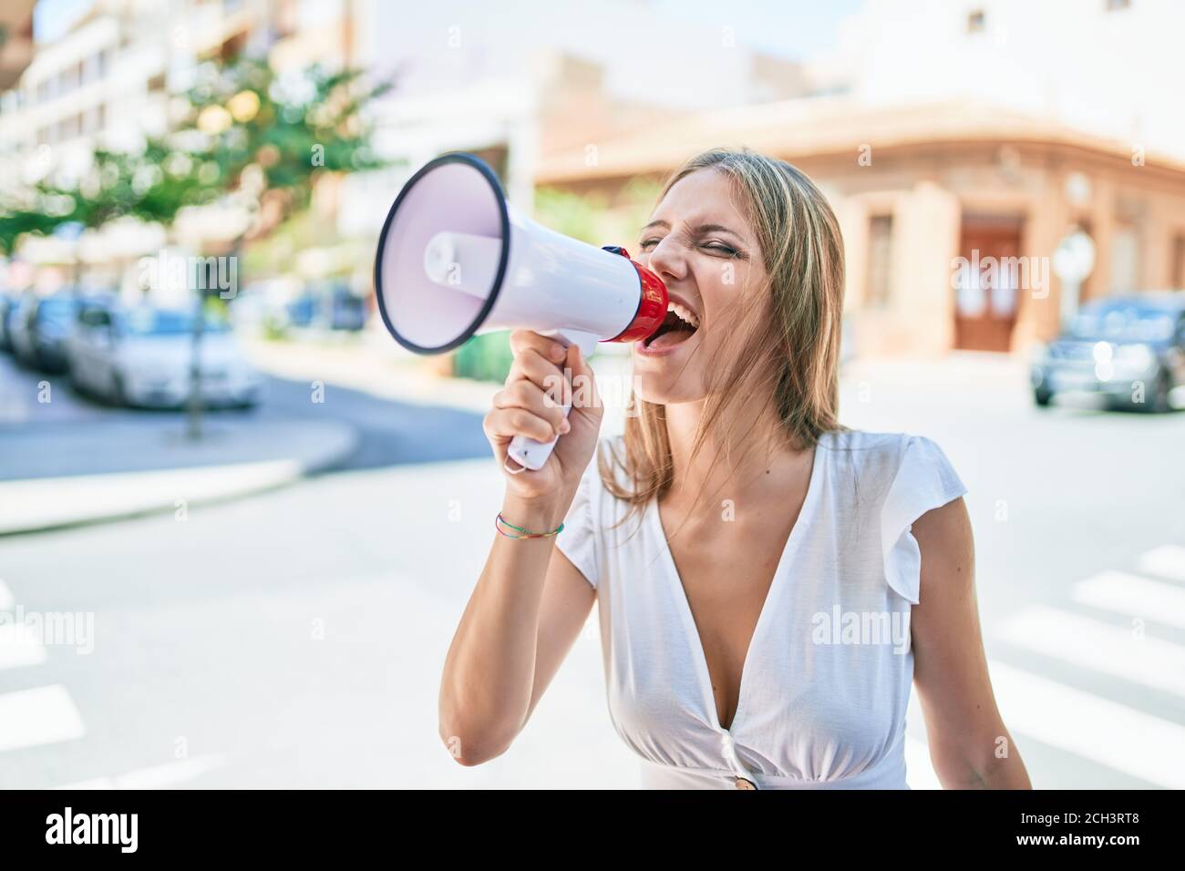 Young caucasian woman screaming using megaphone at the city Stock Photo ...