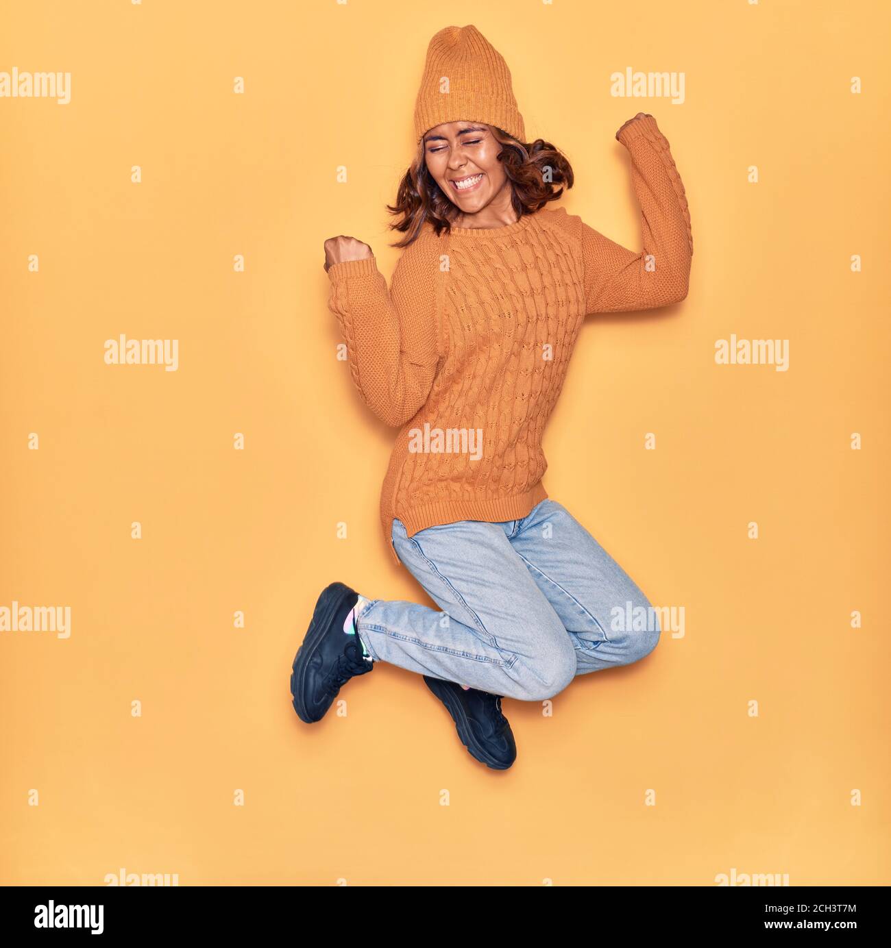 Young beautiful latin woman wearing wool cap and sweater smiling happy ...