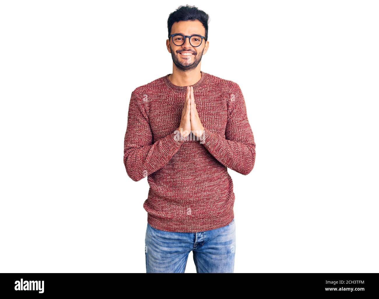 Young handsome hispanic man wearing winter sweater and glasses praying ...