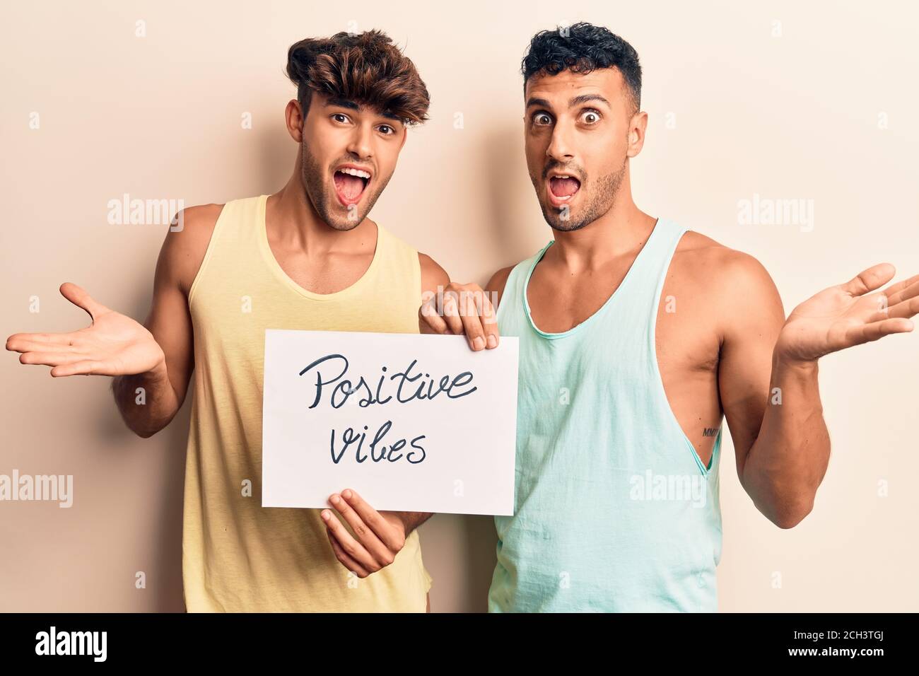 Young gay couple holding positive vibes banner celebrating achievement ...