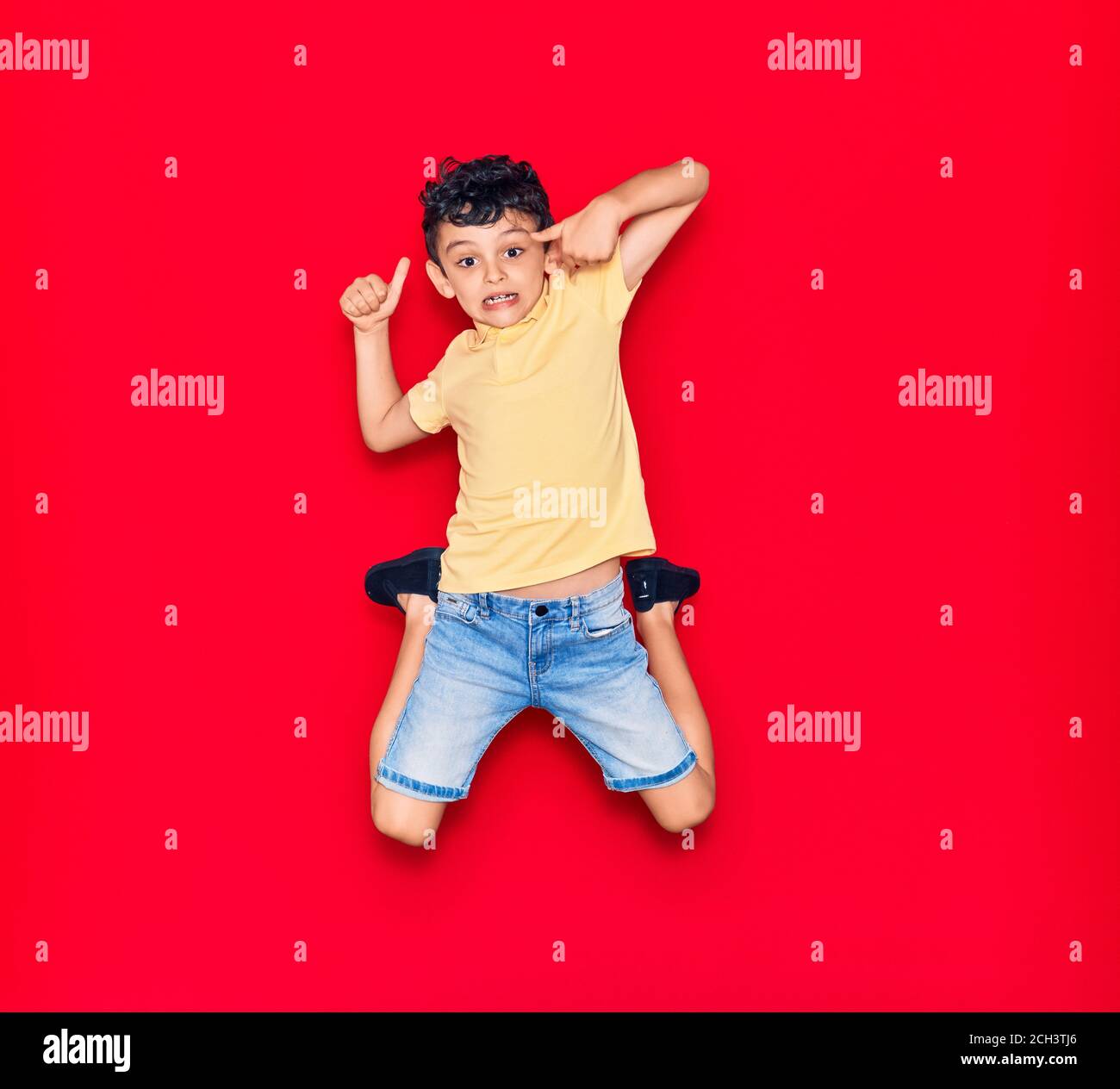 Adorable kid wearing casual clothes jumping over isolated red ...