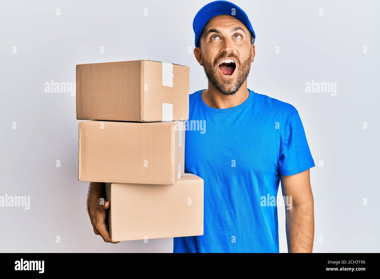 Handsome man with beard wearing courier uniform holding delivery ...