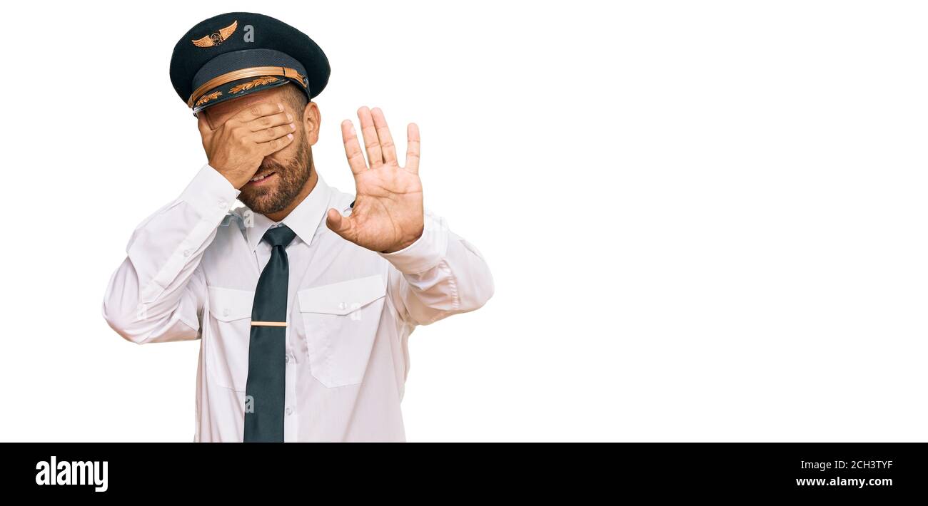 Handsome man with beard wearing airplane pilot uniform covering eyes ...