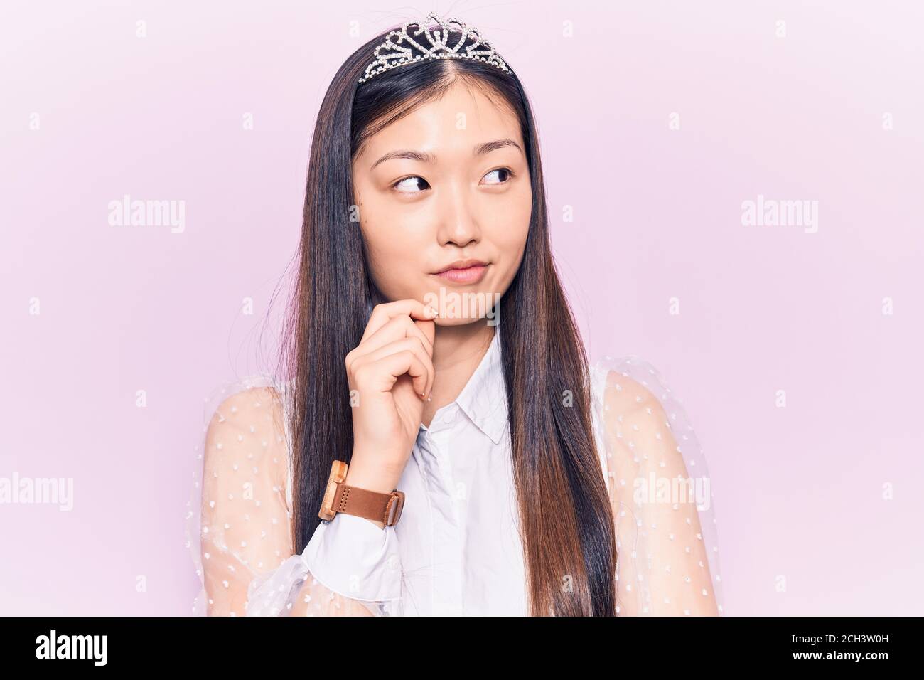 Young beautiful chinese woman wearing princess crown thinking ...