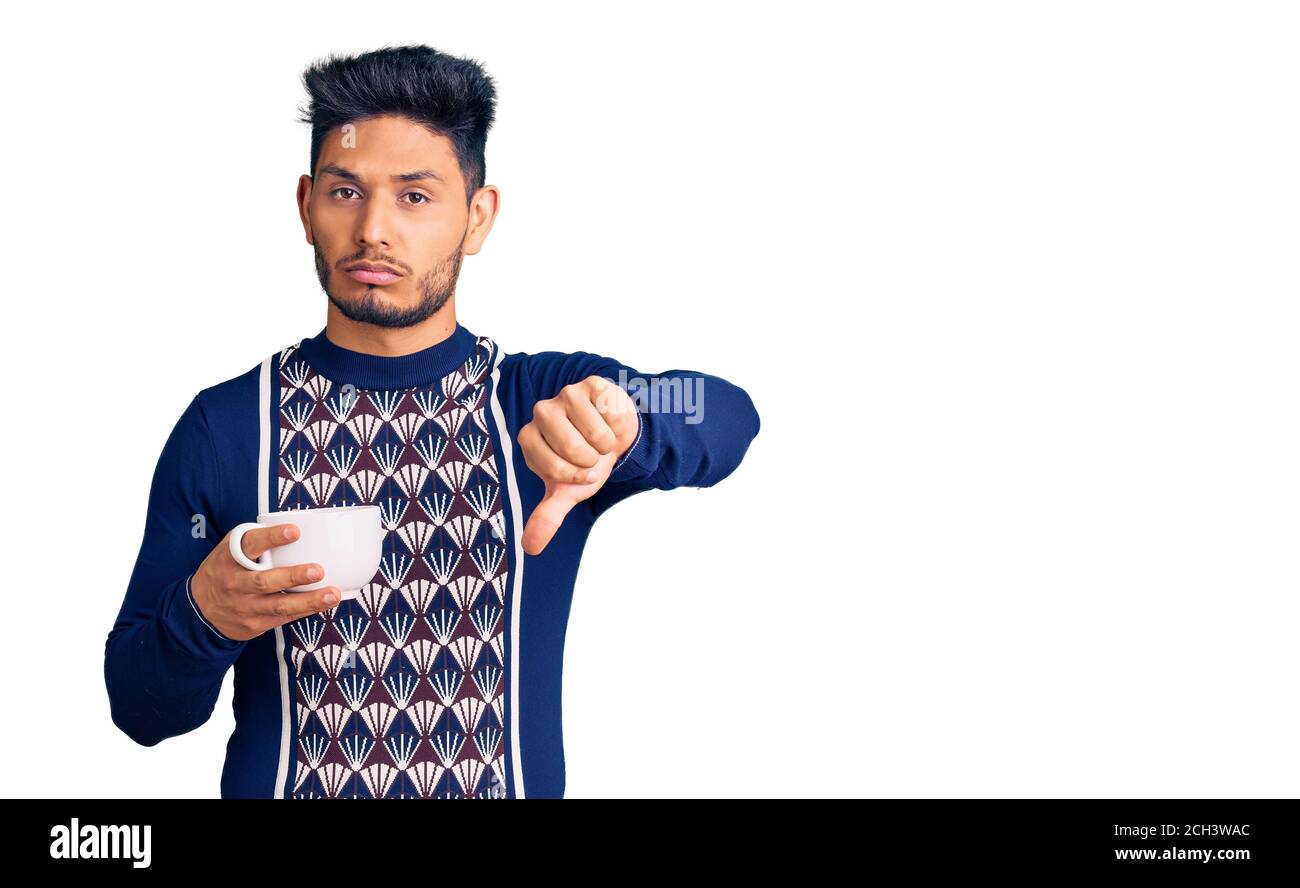 Handsome latin american young man drinking a cup of coffee with angry ...