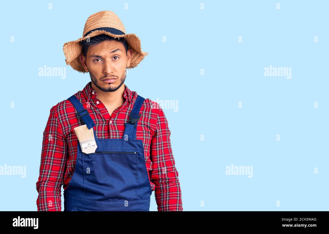 Handsome latin american young man weaing handyman uniform skeptic and ...