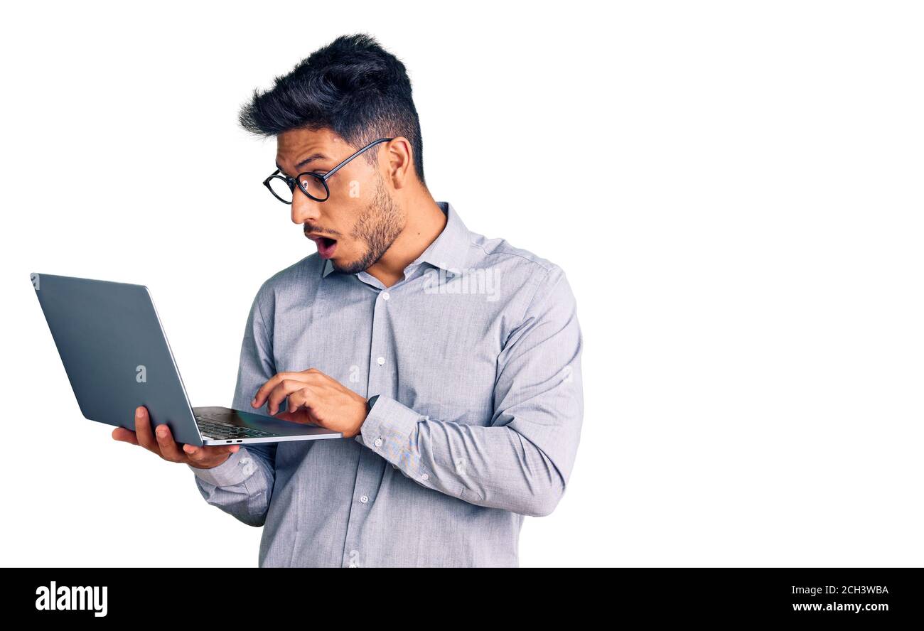 Handsome latin american young man working using computer laptop scared ...