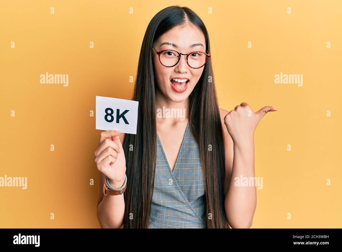 Young chinese woman holding 8k resolution technology paper pointing ...