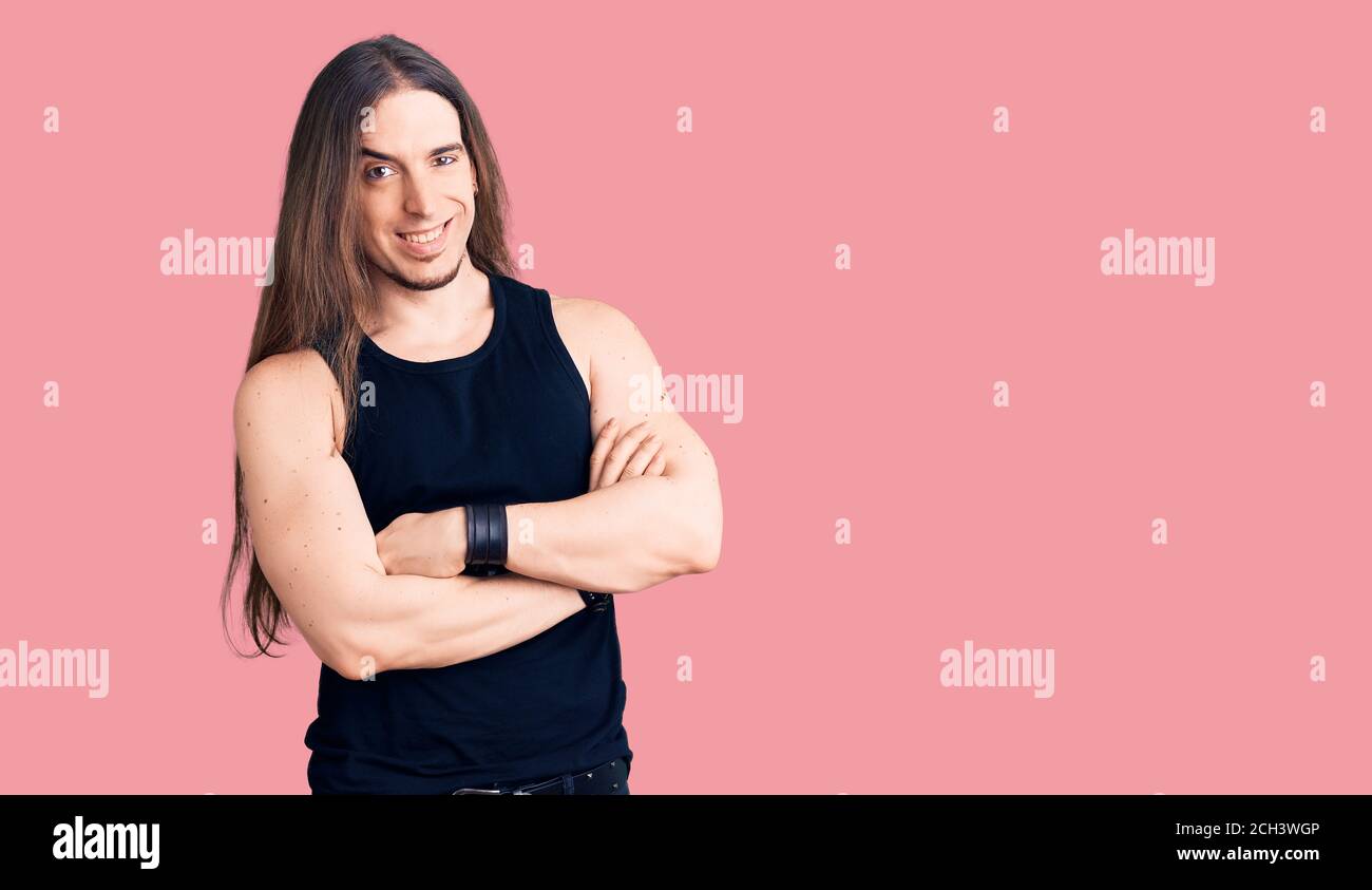 Young adult man with long hair wearing goth style with black clothes ...