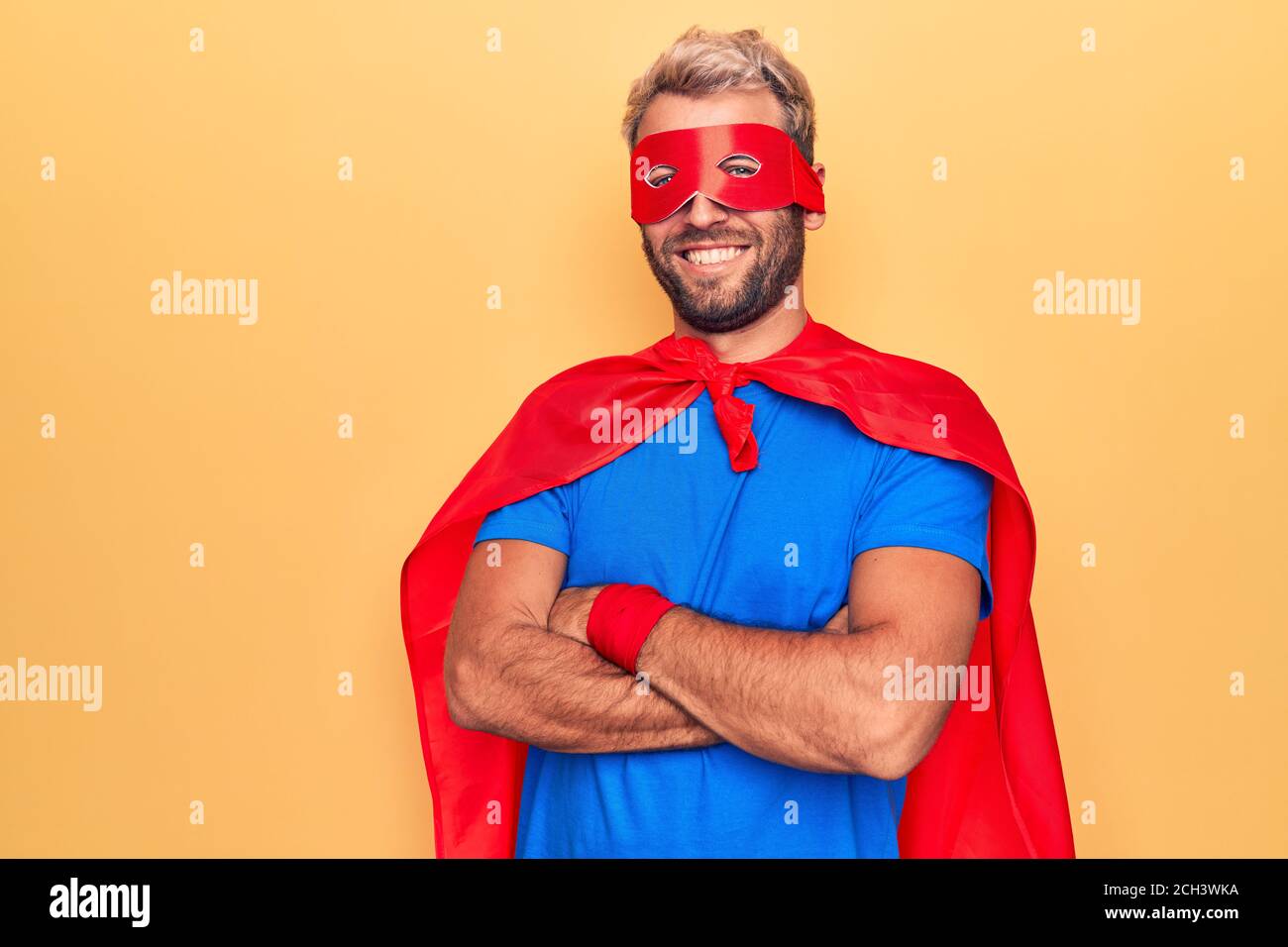 Handsome blond man wearing super hero costume with mask and cape over ...