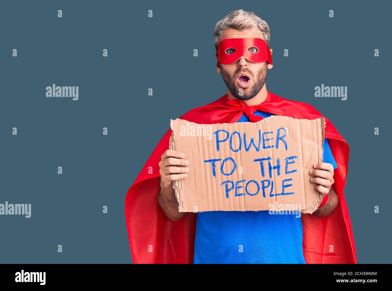 Young blond man wearing super hero custome holding power to the people ...