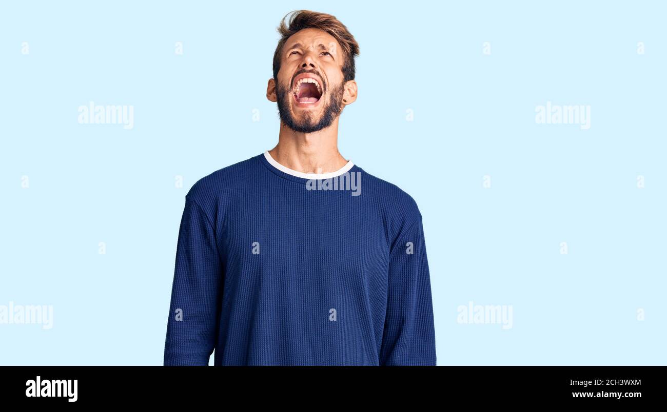 Handsome blond man with beard wearing casual sweater angry and mad ...