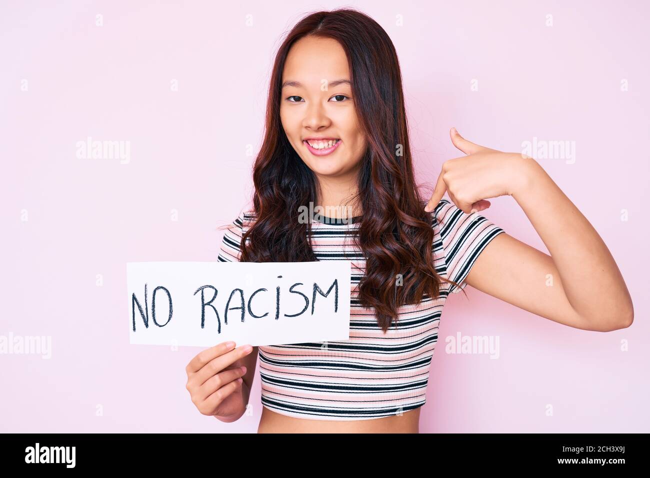 Young beautiful chinese girl holding no racism banner pointing finger ...