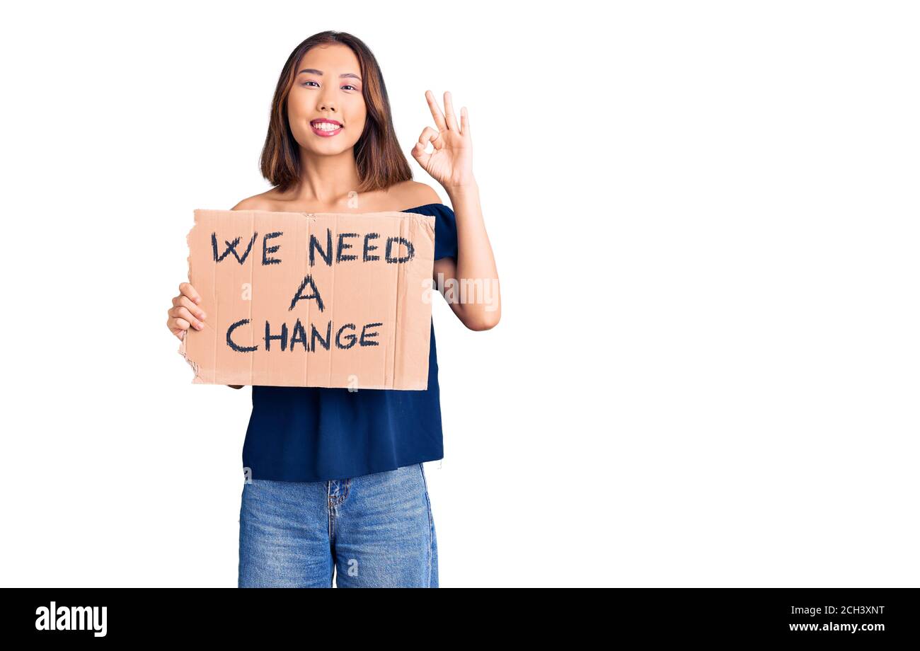 Young beautiful chinese girl holding we need a change banner doing ok ...