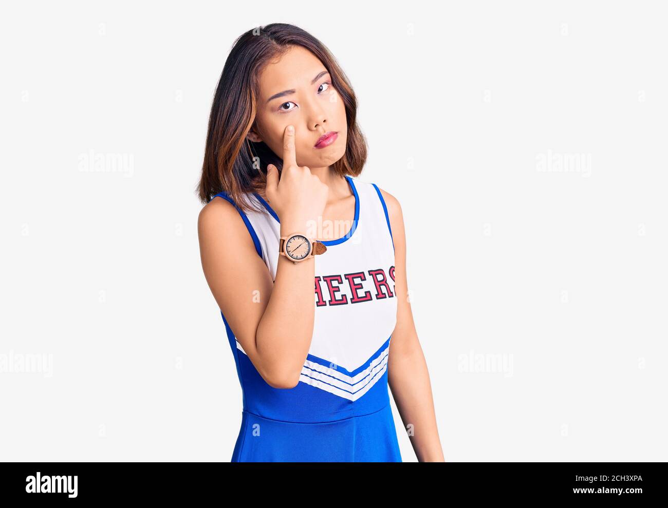Young beautiful chinese girl wearing cheerleader uniform pointing to ...