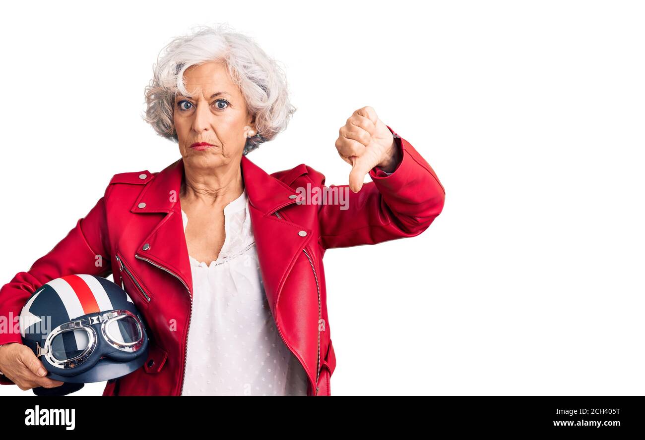 Senior grey-haired woman holding motorcycle helmet with angry face ...