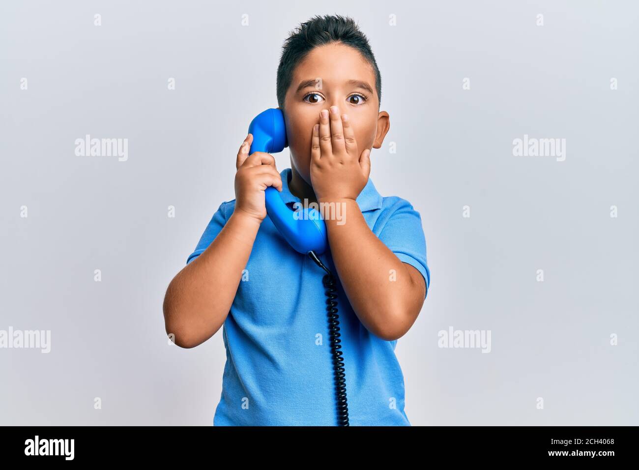 Little boy hispanic kid talking through vintage telephone covering ...