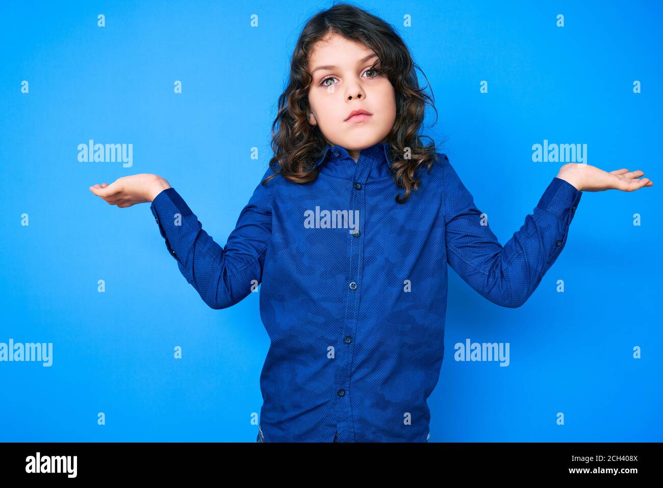 Cute hispanic child with long hair wearing casual clothes clueless and ...