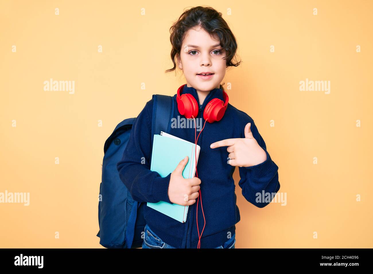 Cute hispanic child holding student backpack and books smiling happy ...
