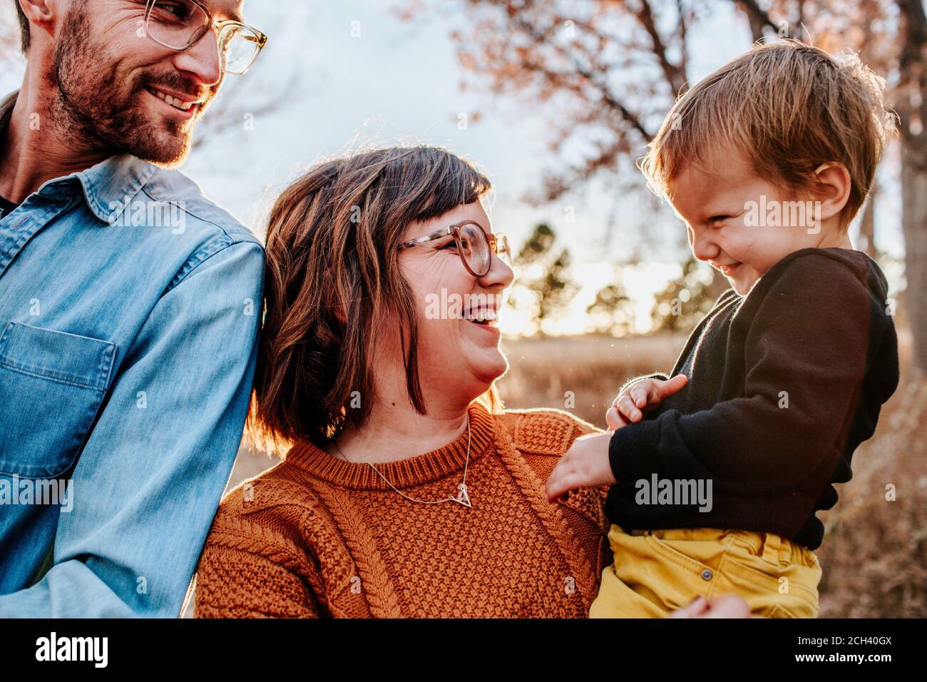 Parents smiling and laughing at young child on a fall evening Stock ...