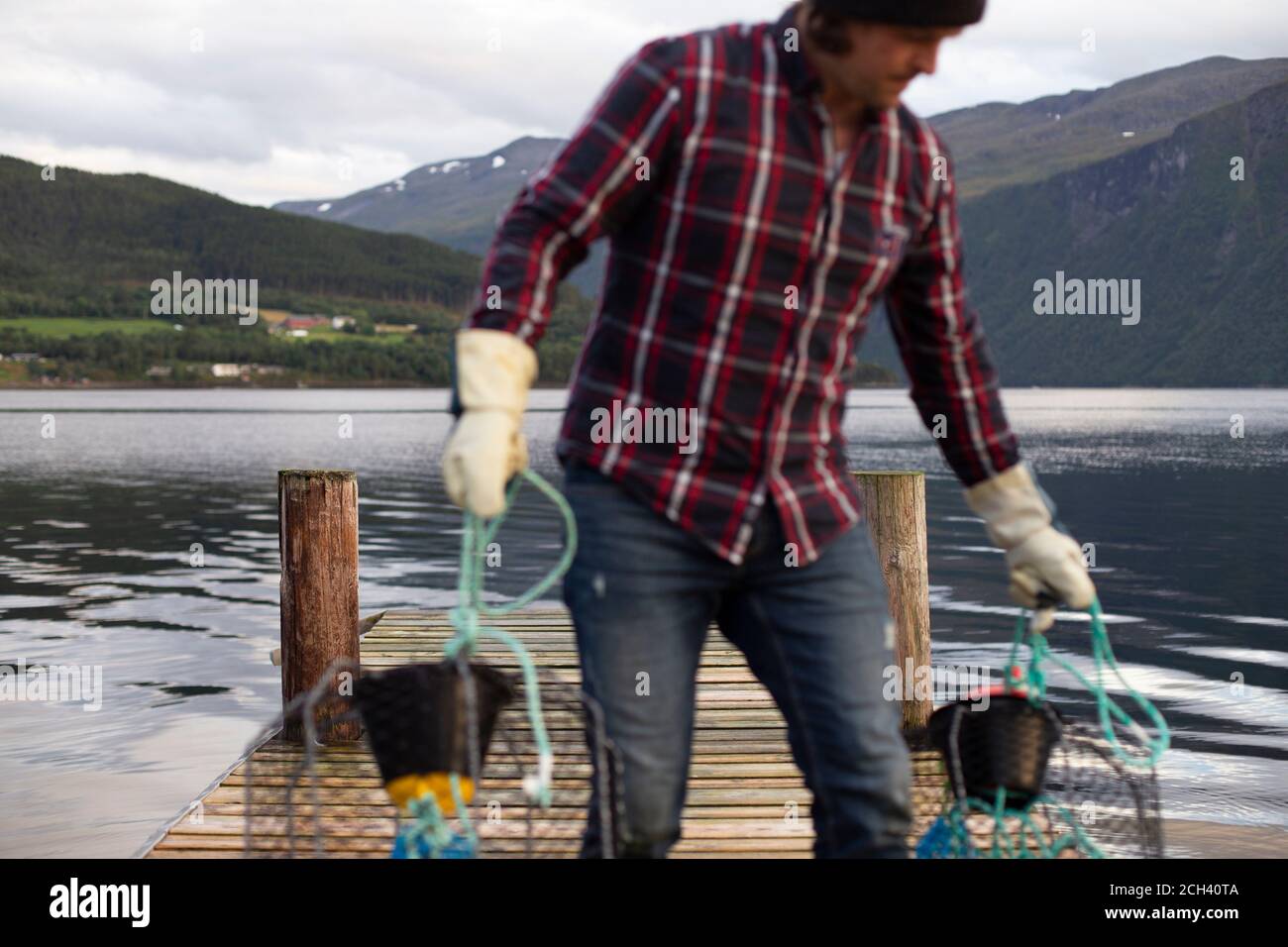 Out of focus fisherman carrying crab pots on a lake Stock Photo - Alamy