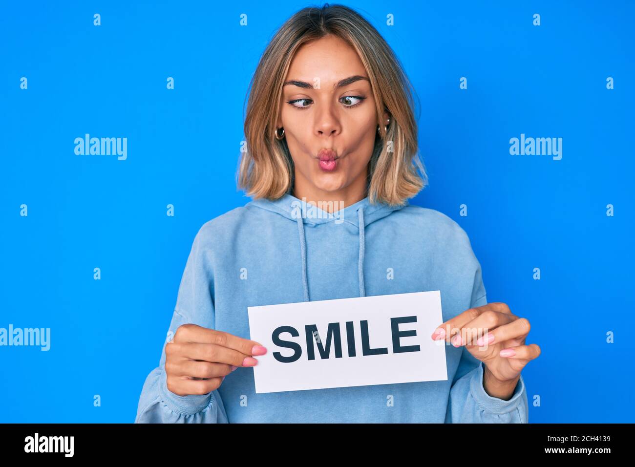 Beautiful caucasian woman holding smile text making fish face with ...