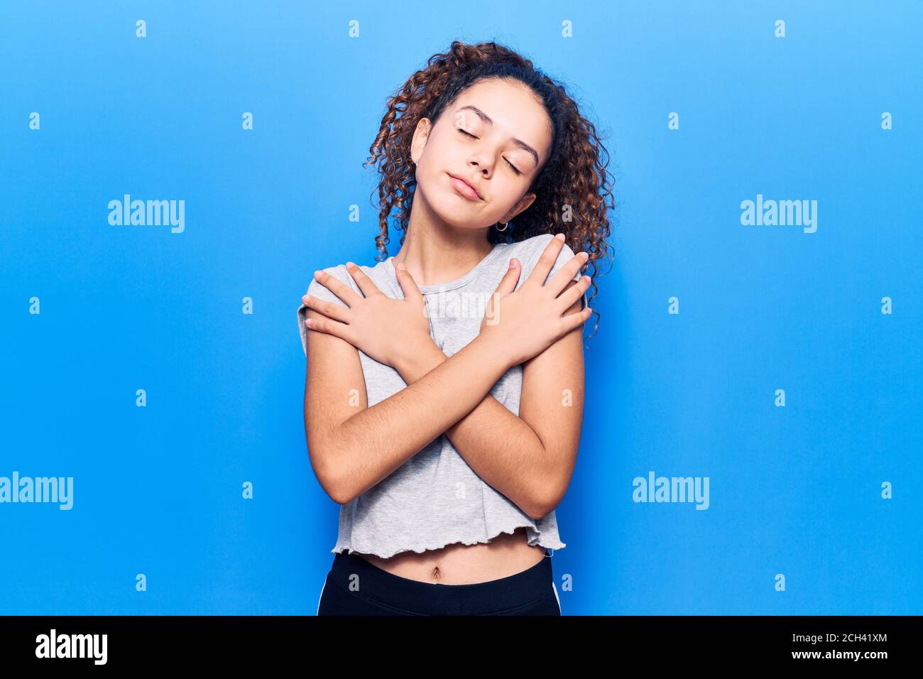 Beautiful kid girl with curly hair wearing casual clothes hugging ...