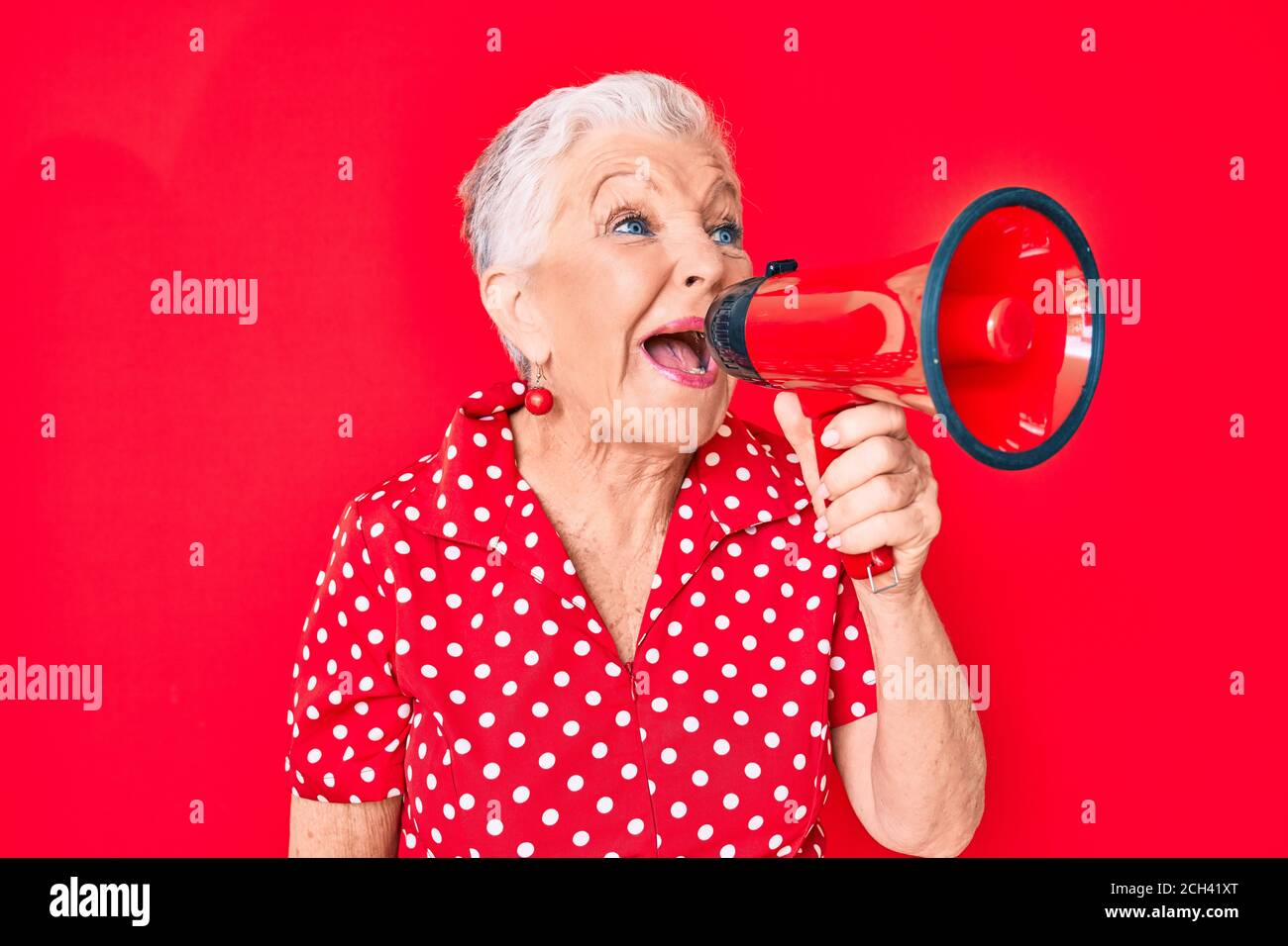 Senior beautiful grey-haired woman screaming using megaphone over ...