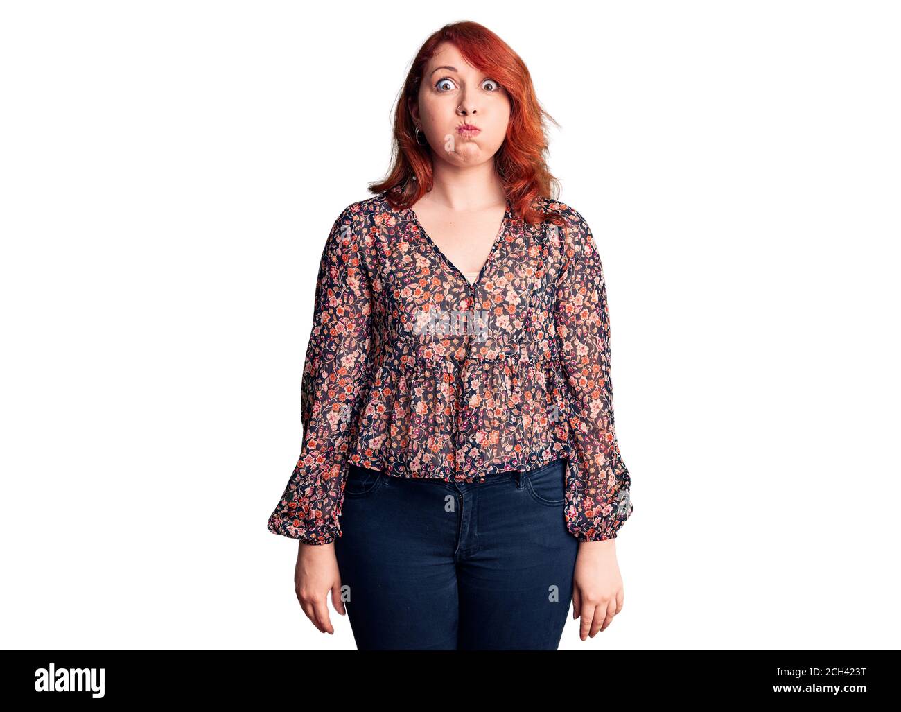 Young beautiful redhead woman wearing casual t-shirt puffing cheeks ...