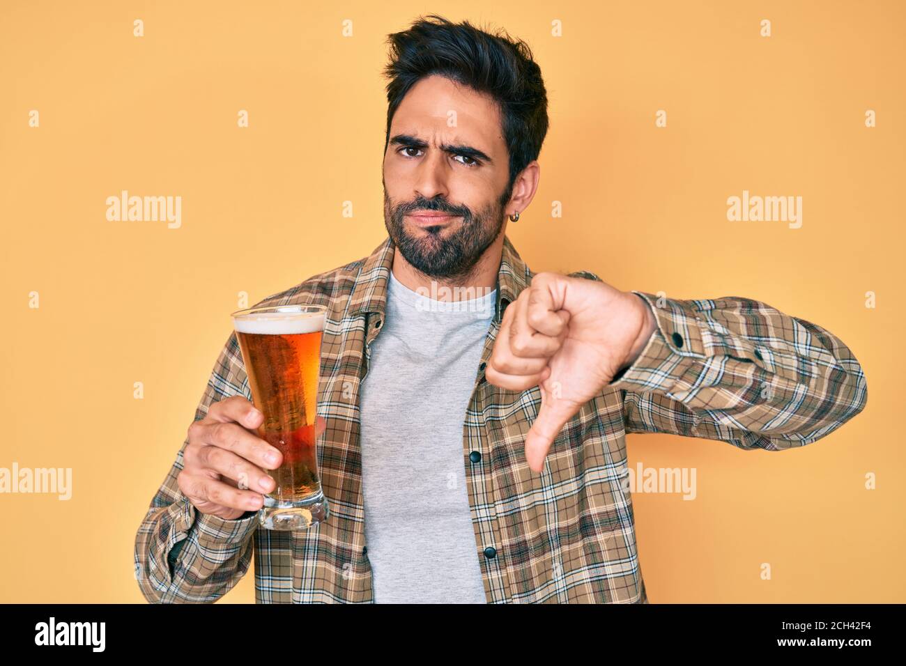 Handsome hispanic man with beard drinking a pint of beer with angry ...