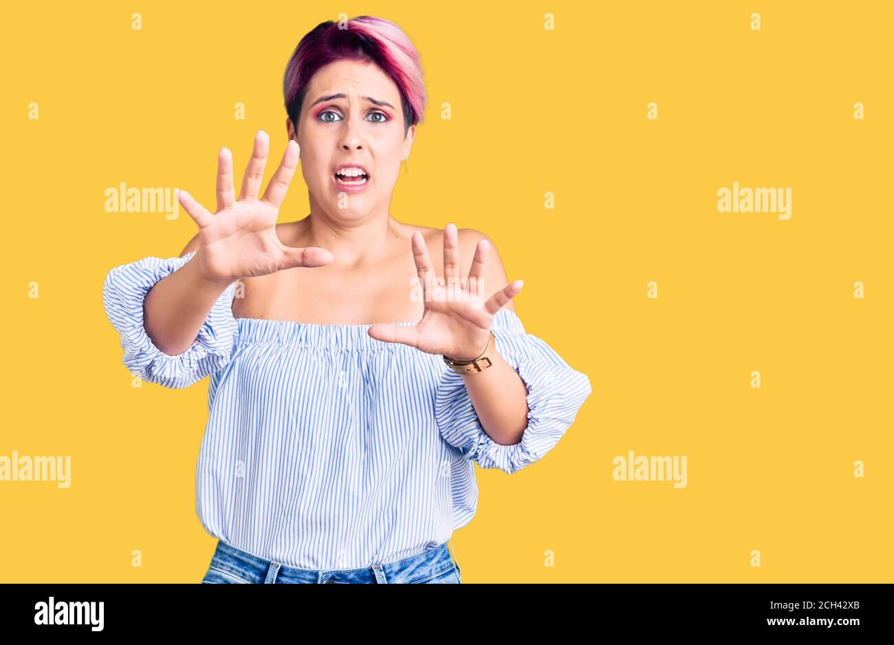 Young beautiful woman with pink hair wearing casual clothes afraid and ...