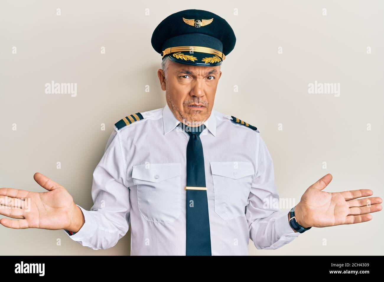 Handsome middle age mature man wearing airplane pilot uniform clueless ...