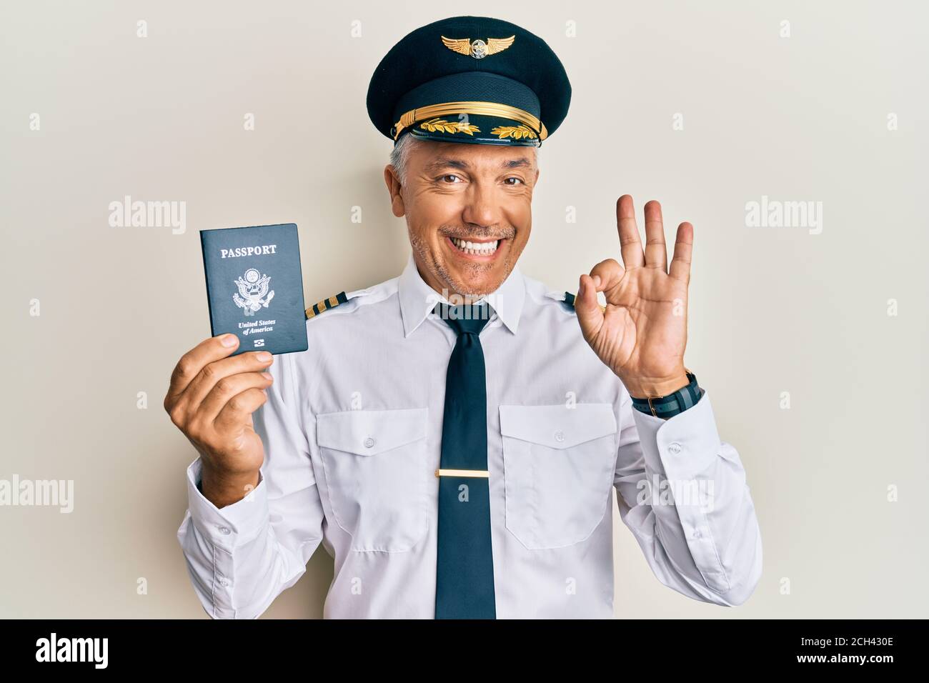 Handsome middle age mature pilot man holding usa passport doing ok sign ...