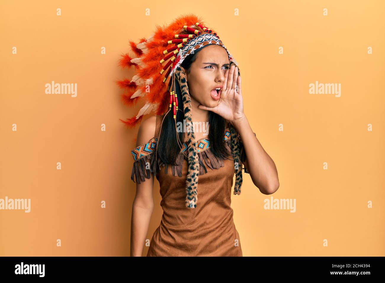 Young brunette woman wearing indian costume shouting and screaming loud ...