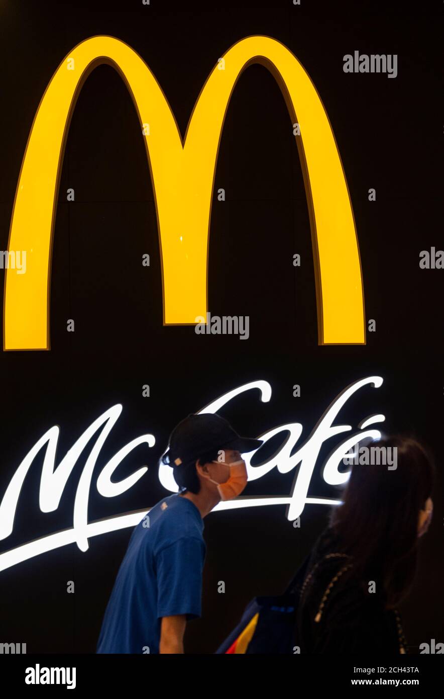 Pedestrians wearing face masks walk past the American multinational ...