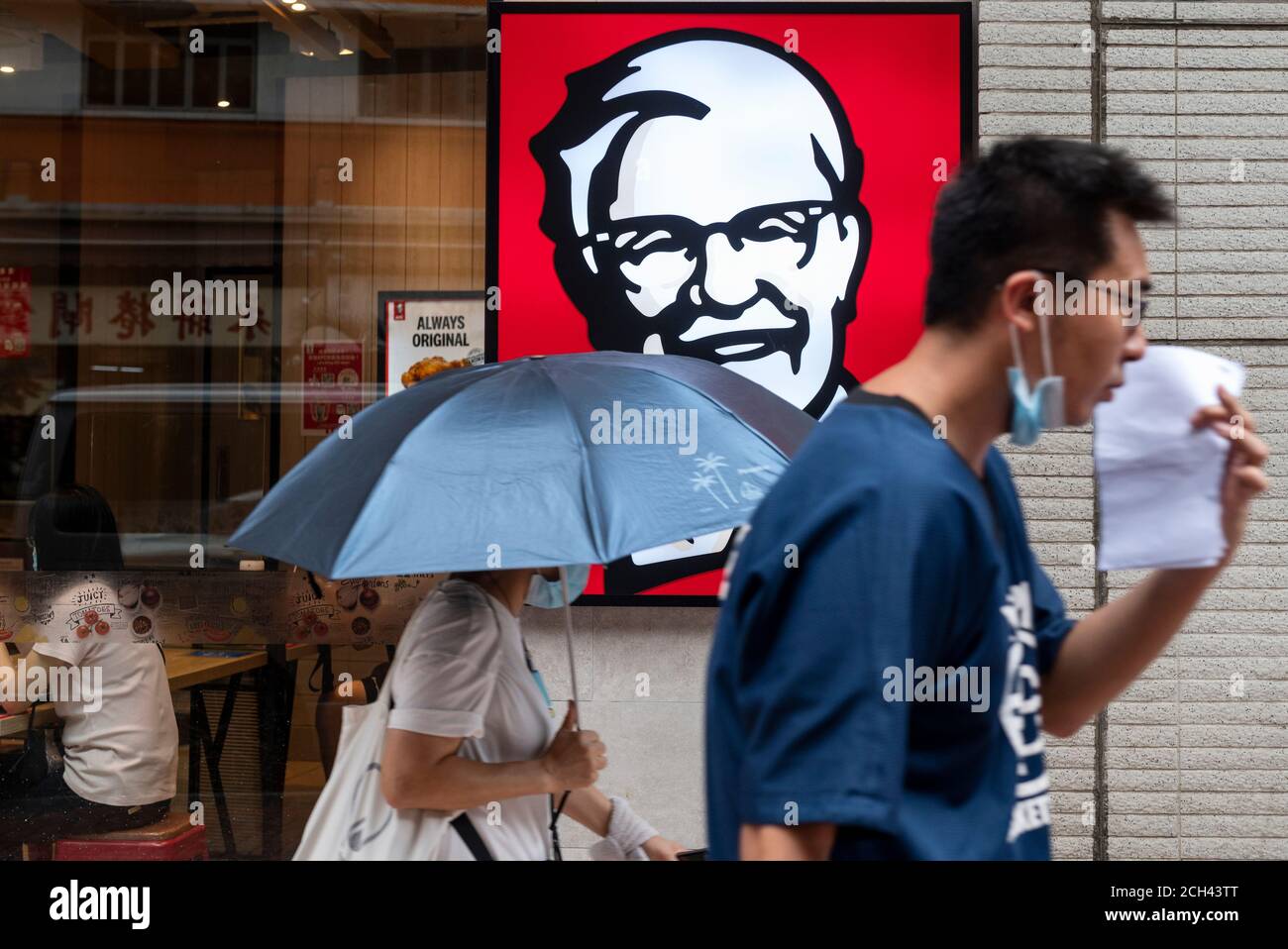 Pedestrians wearing face masks walk past the American fast food chicken ...