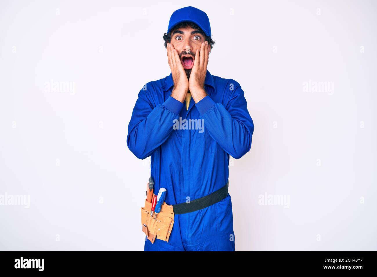 Handsome young man with curly hair and bear weaing handyman uniform ...