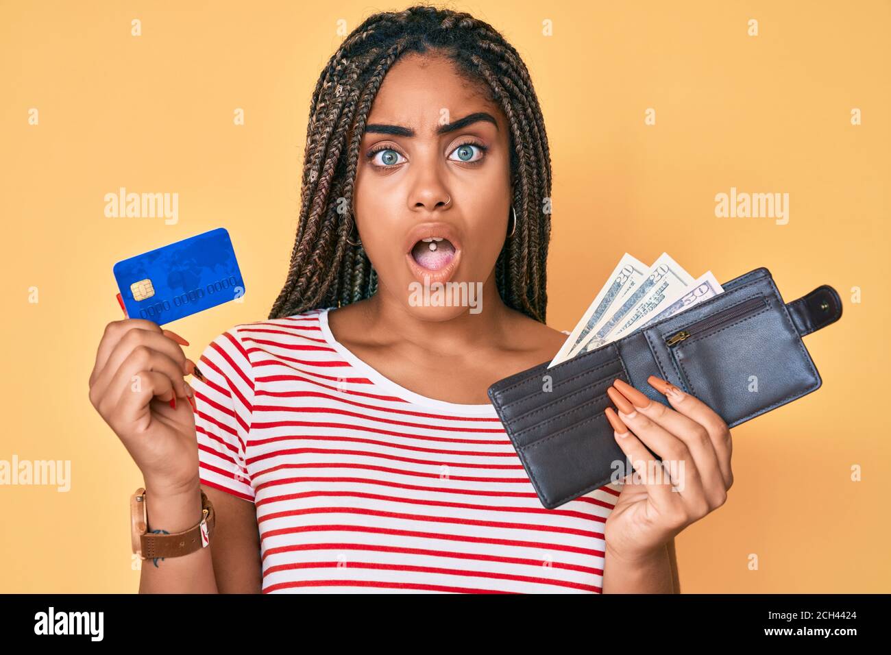 Young african american woman with braids holding wallet with dollars ...