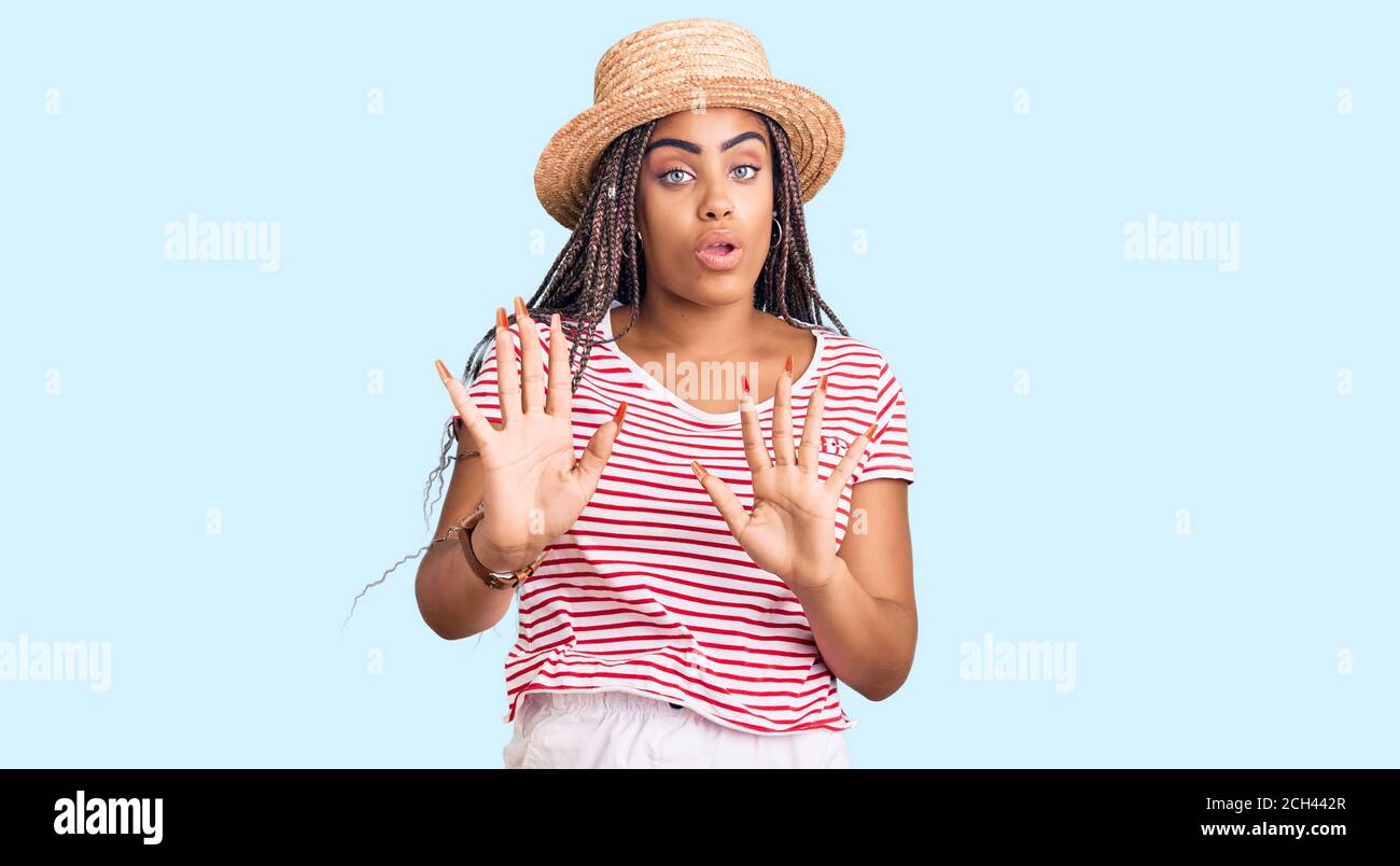 Young african american woman with braids wearing summer hat moving away ...