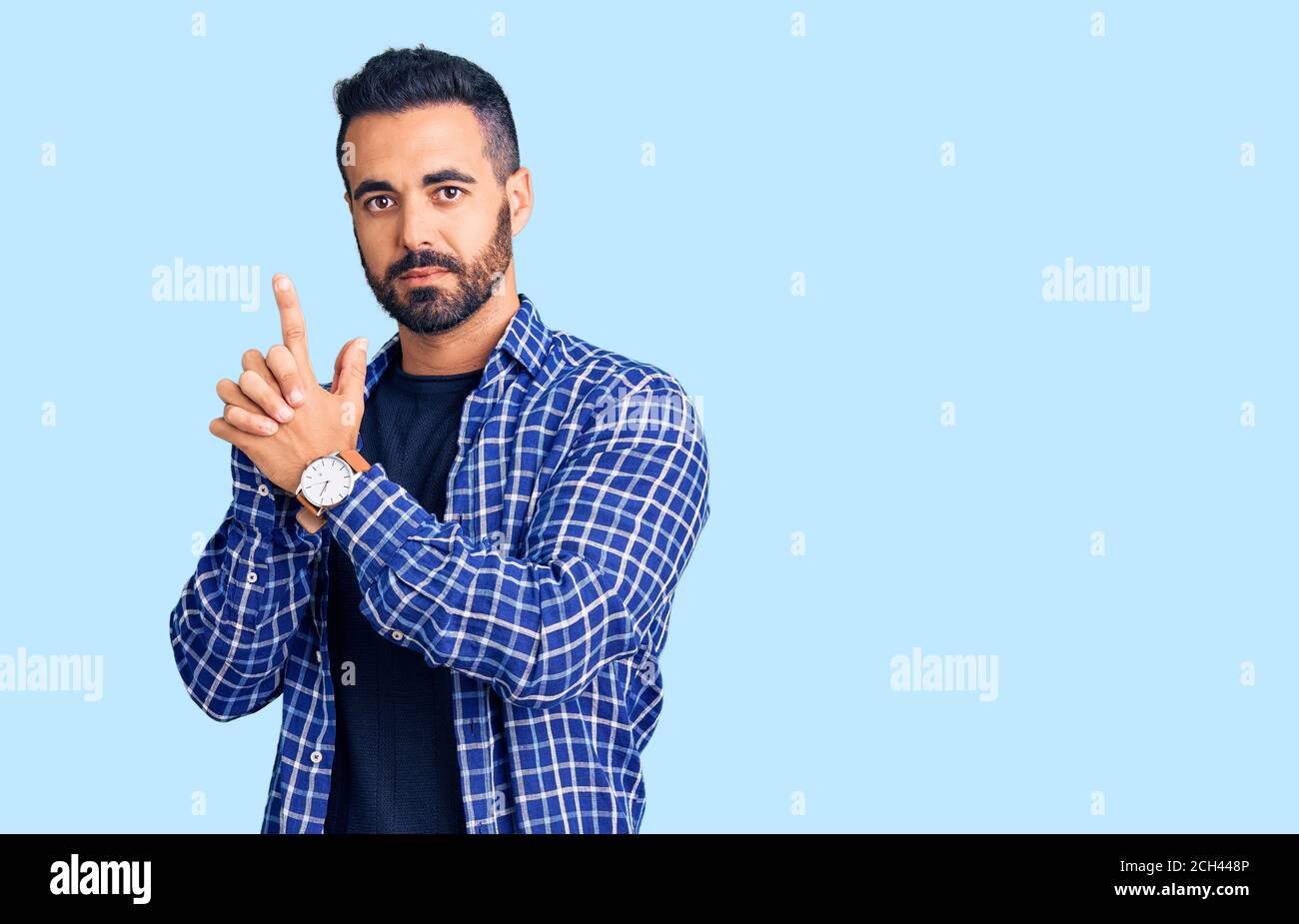 Young hispanic man wearing casual clothes holding symbolic gun with ...