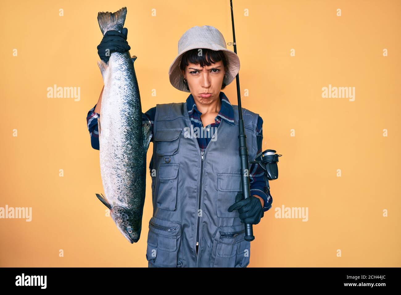 Beautiful brunettte fisher woman holding fishing rod and raw salmon ...