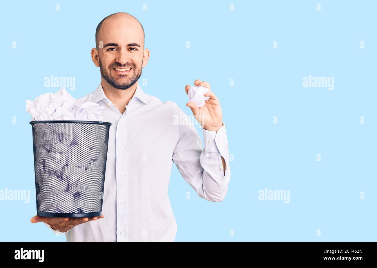 Young handsome man holding paper bin full of crumpled papers looking ...
