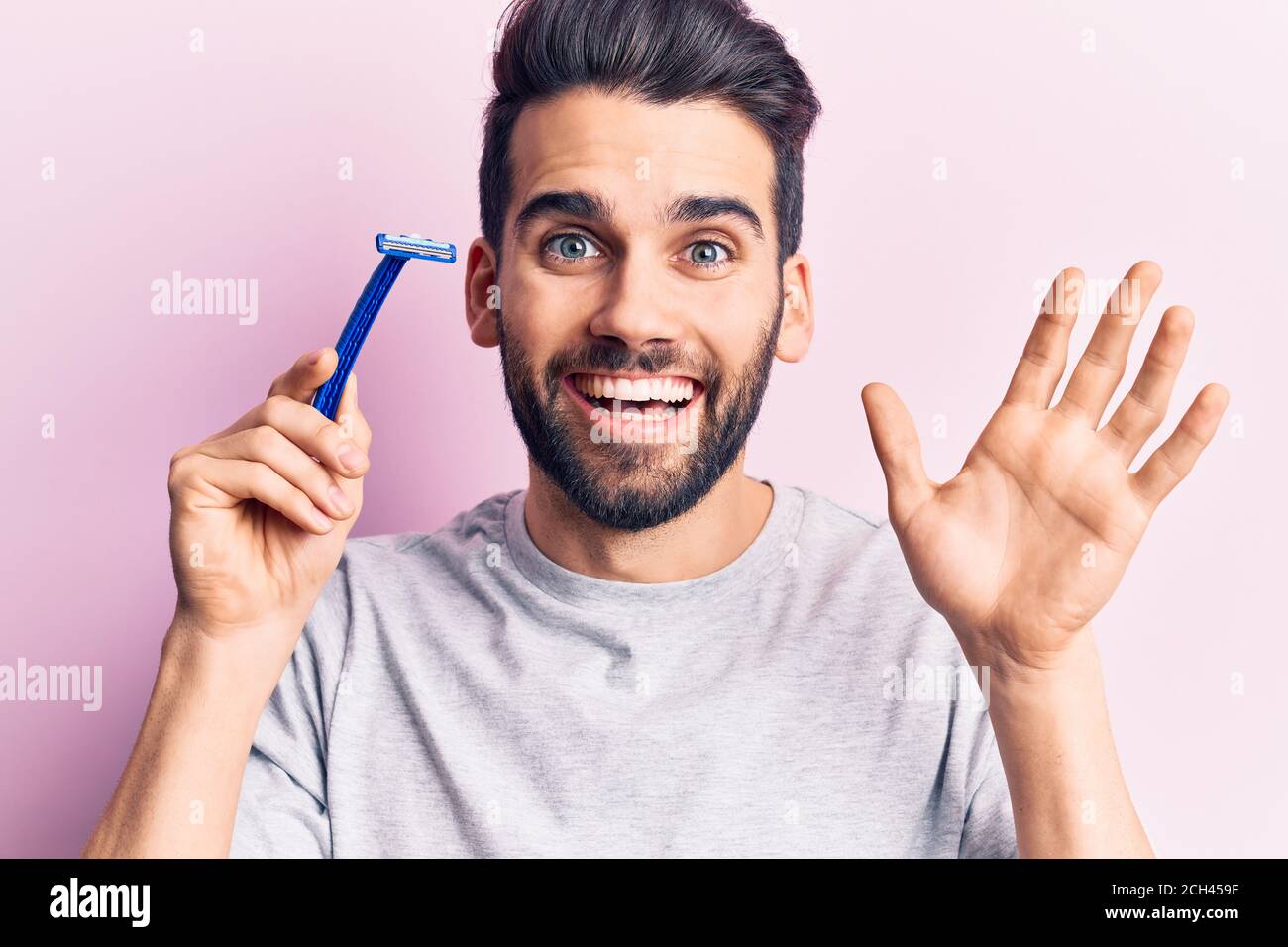Young handsome man with beard holding razor celebrating achievement ...