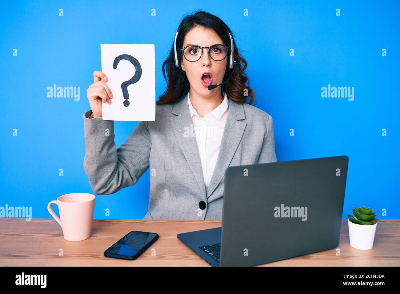 Young beautiful brunette woman wearing operator headset holding ...