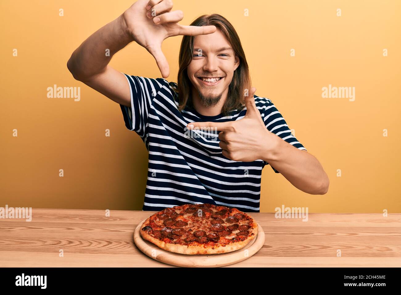 Handsome caucasian man with long hair eating tasty pepperoni pizza ...